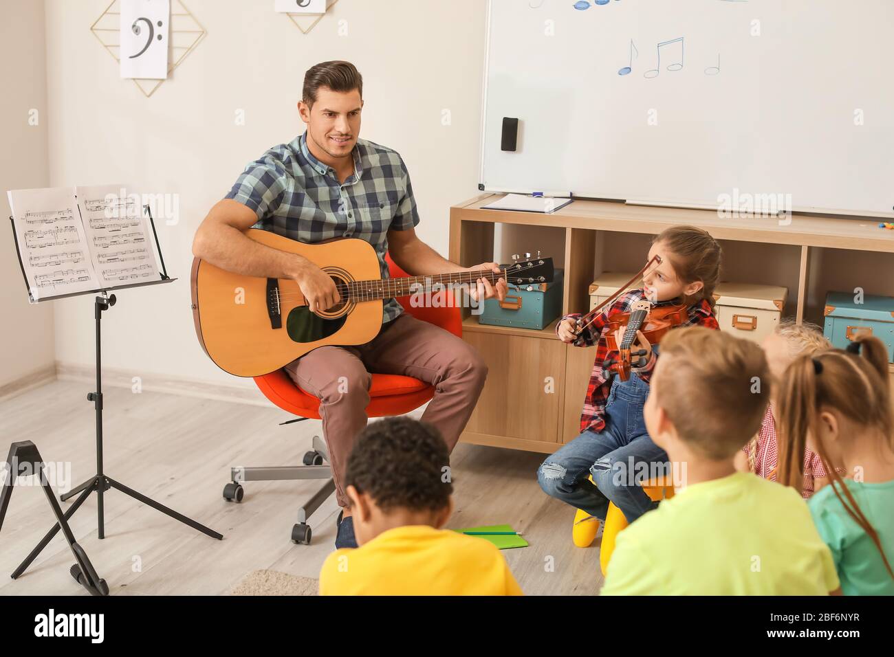 Teacher giving music lessons at school Stock Photo - Alamy