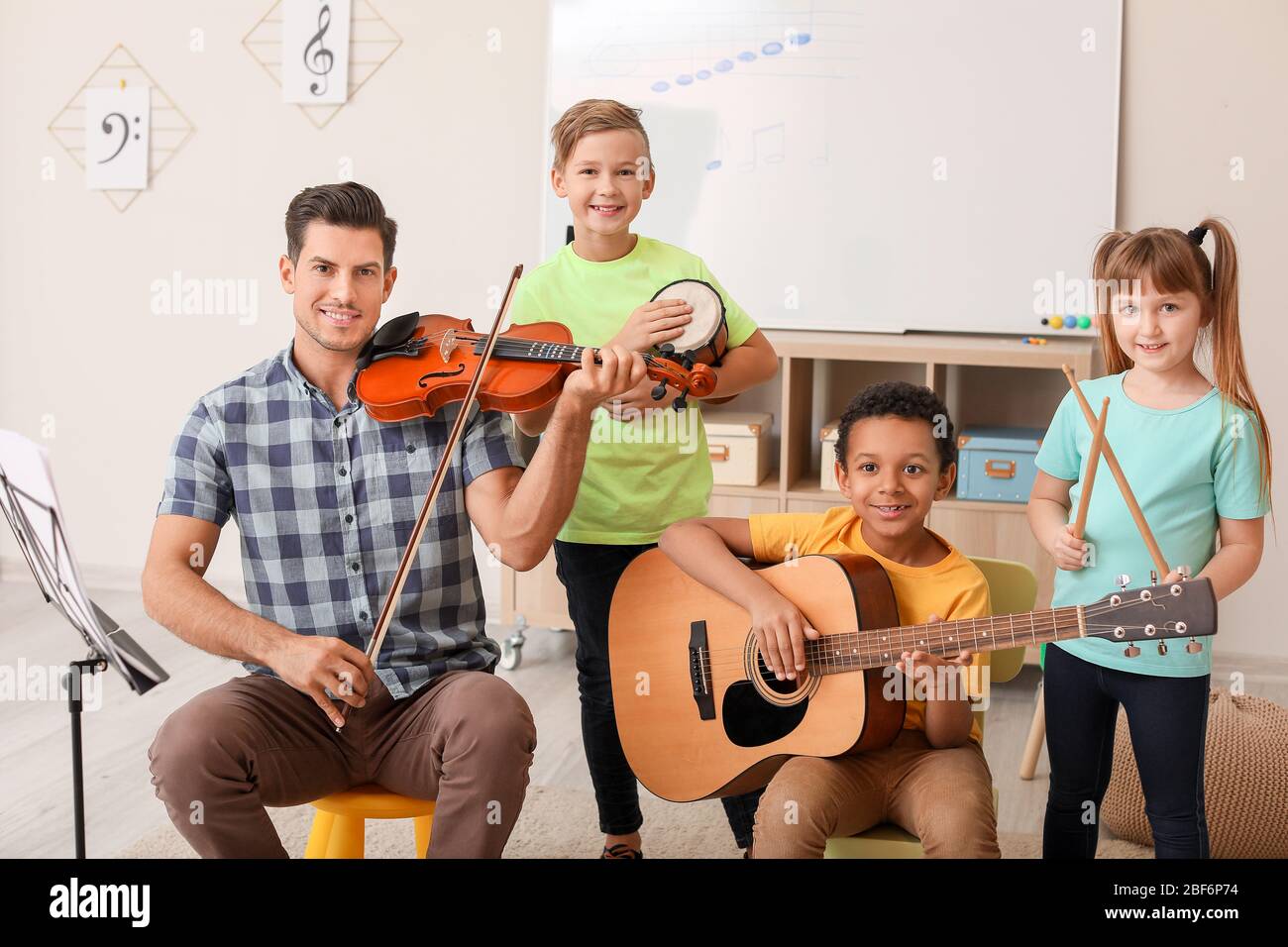 Teacher giving music lessons at school Stock Photo - Alamy