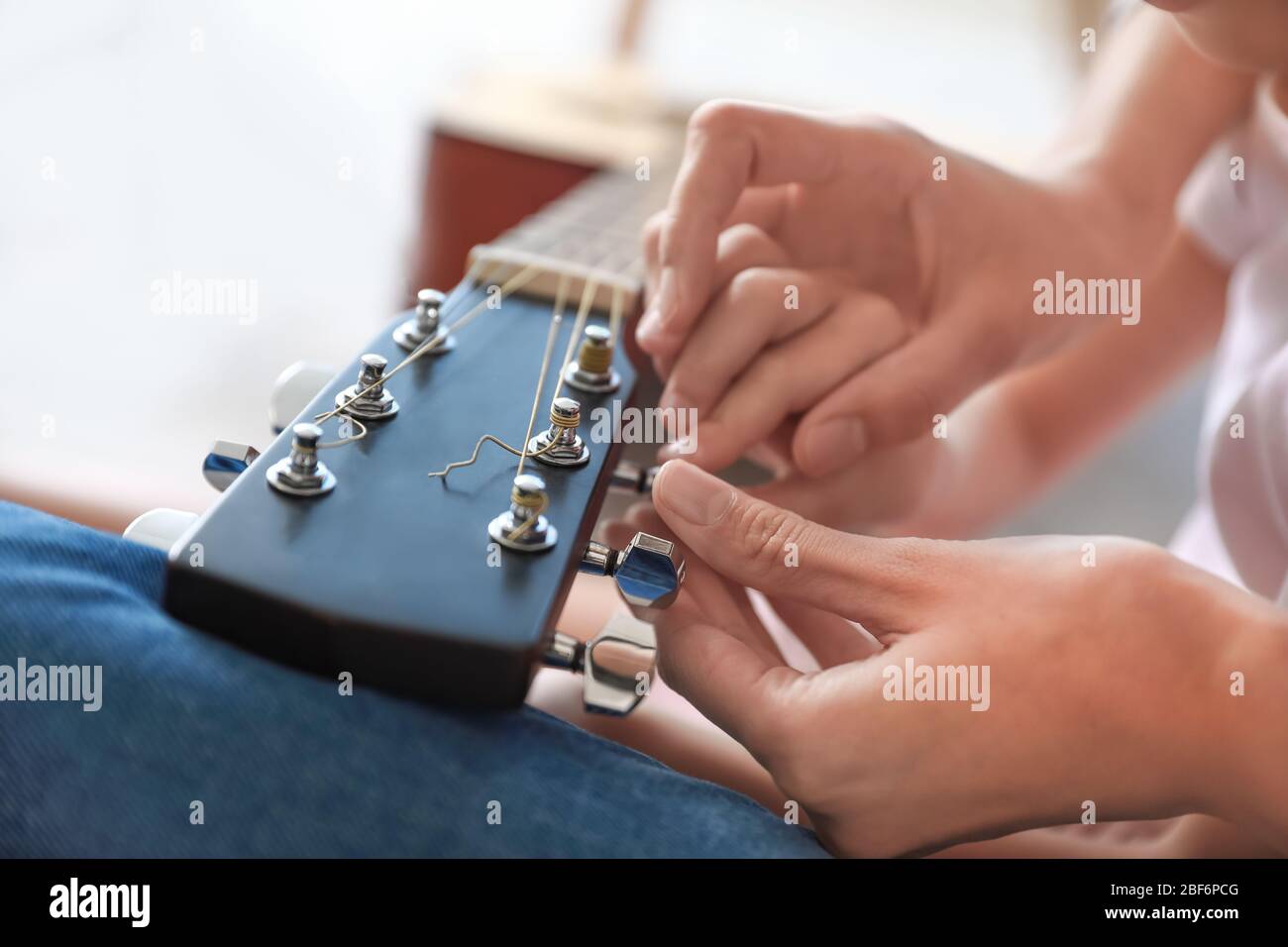 Private music teacher giving guitar lessons to little girl at home ...