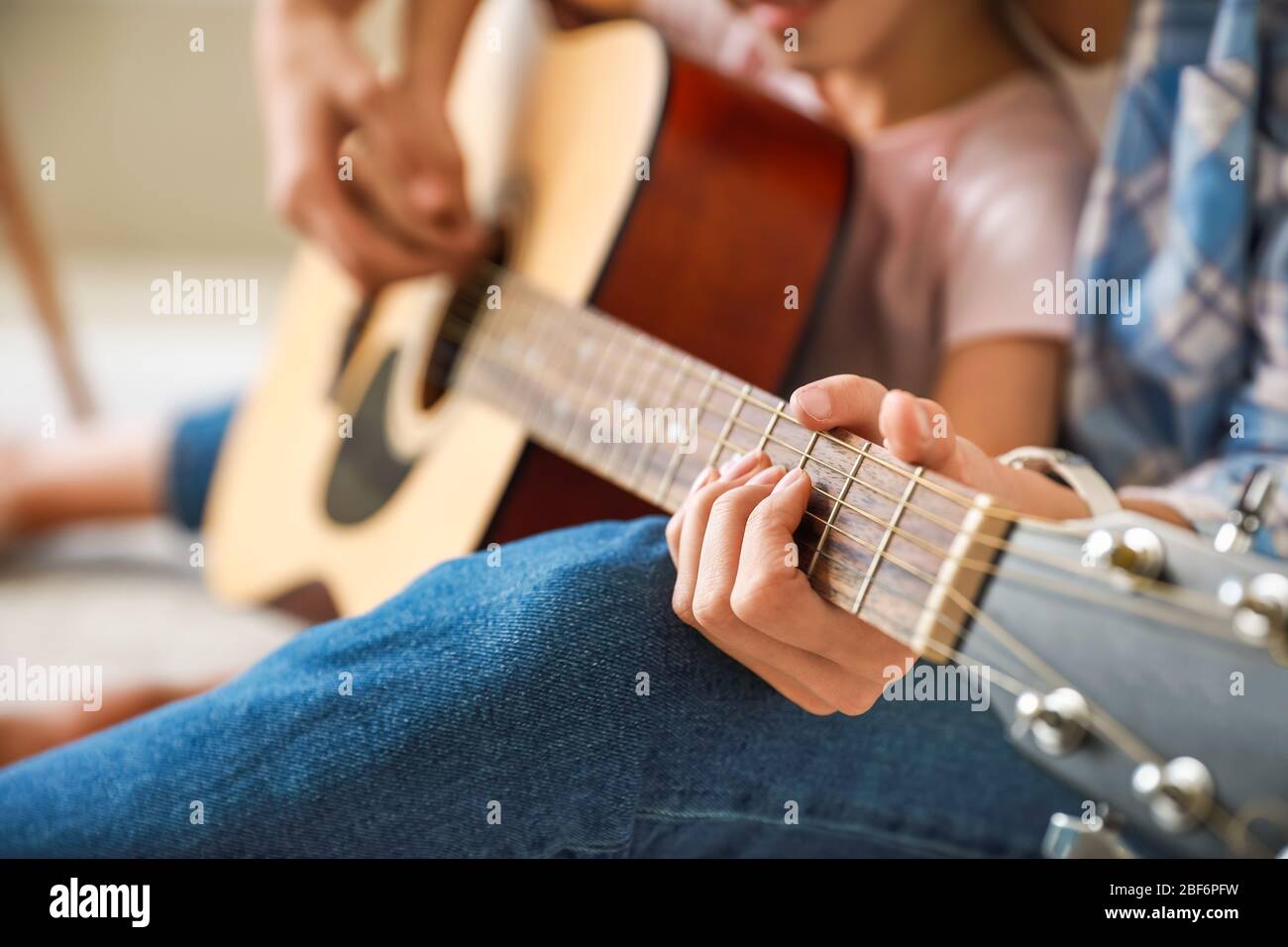 Private music teacher giving guitar lessons to little girl at home ...