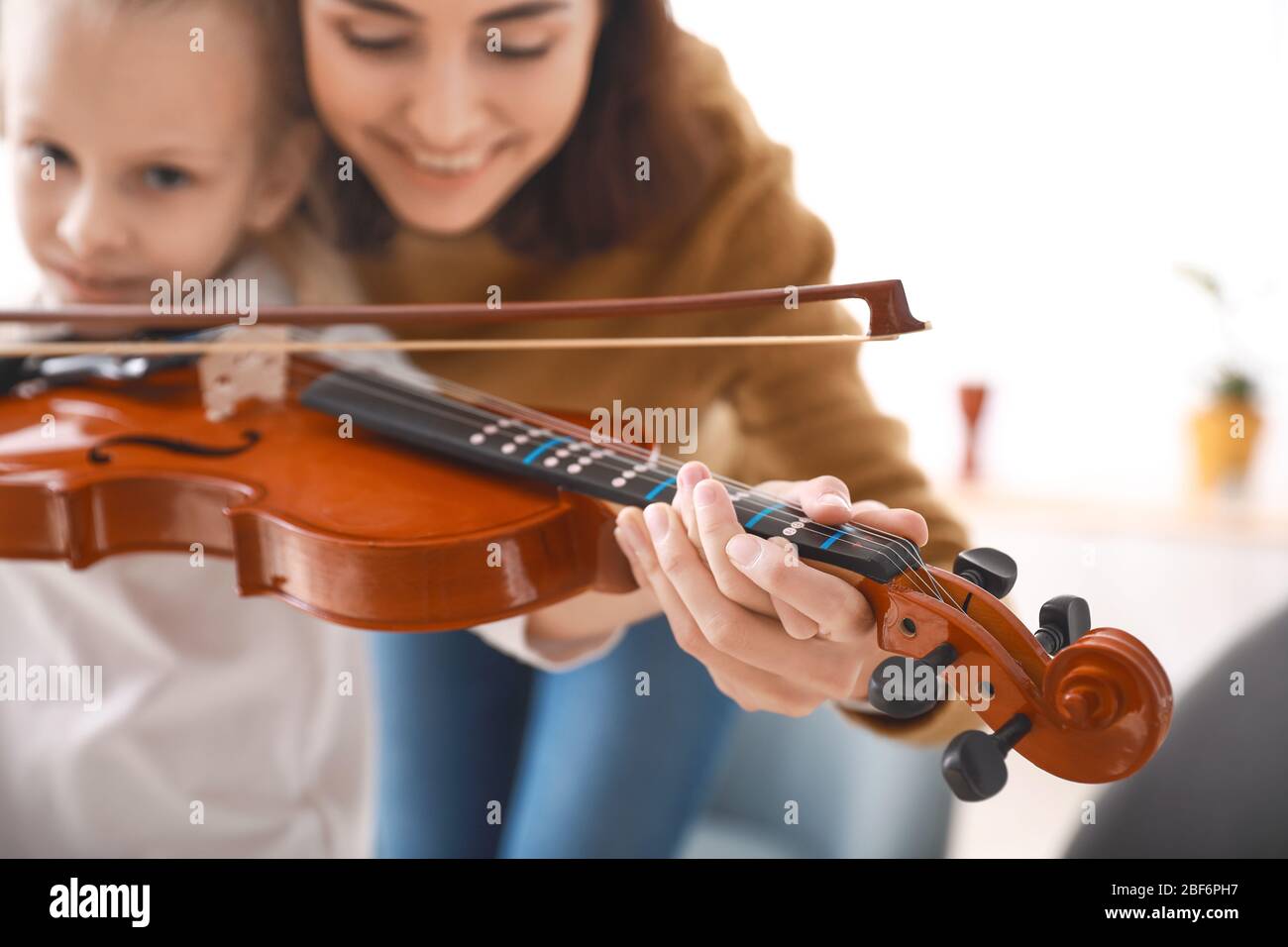Private music teacher giving violin lessons to little girl at home ...