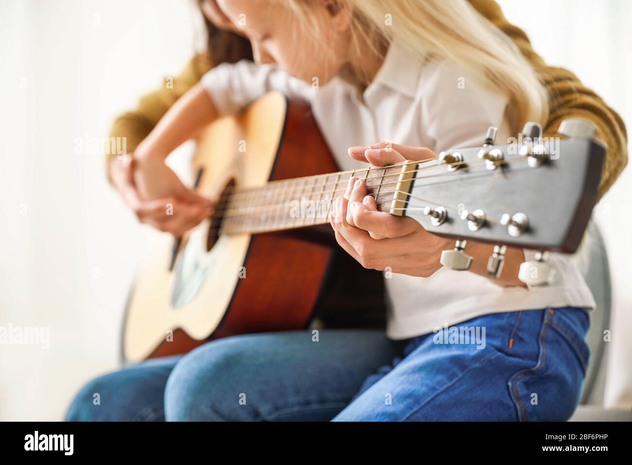 Private music teacher giving guitar lessons to little girl at home ...