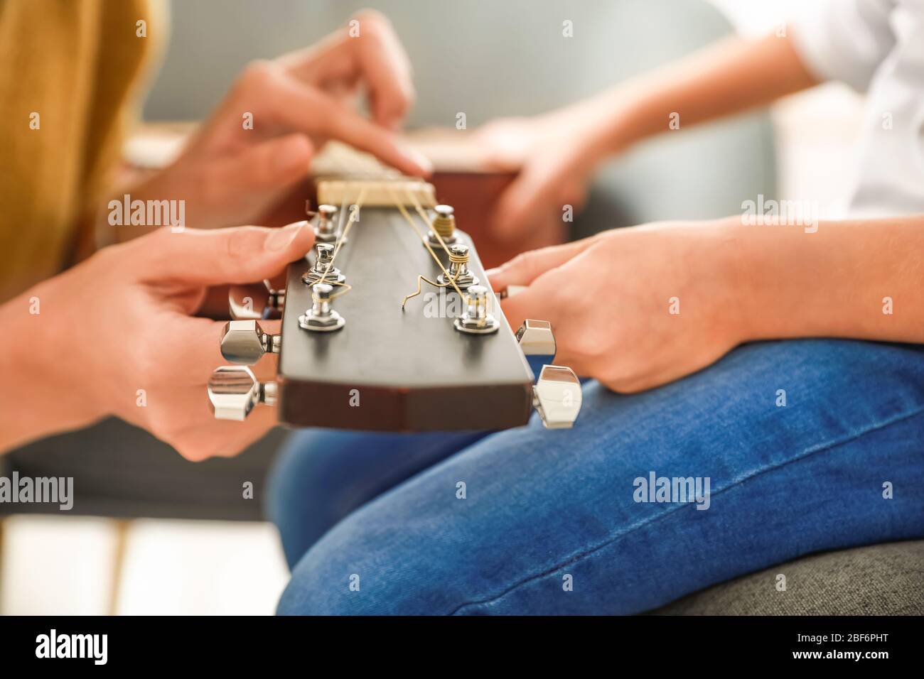 Private music teacher giving guitar lessons to little girl at home ...