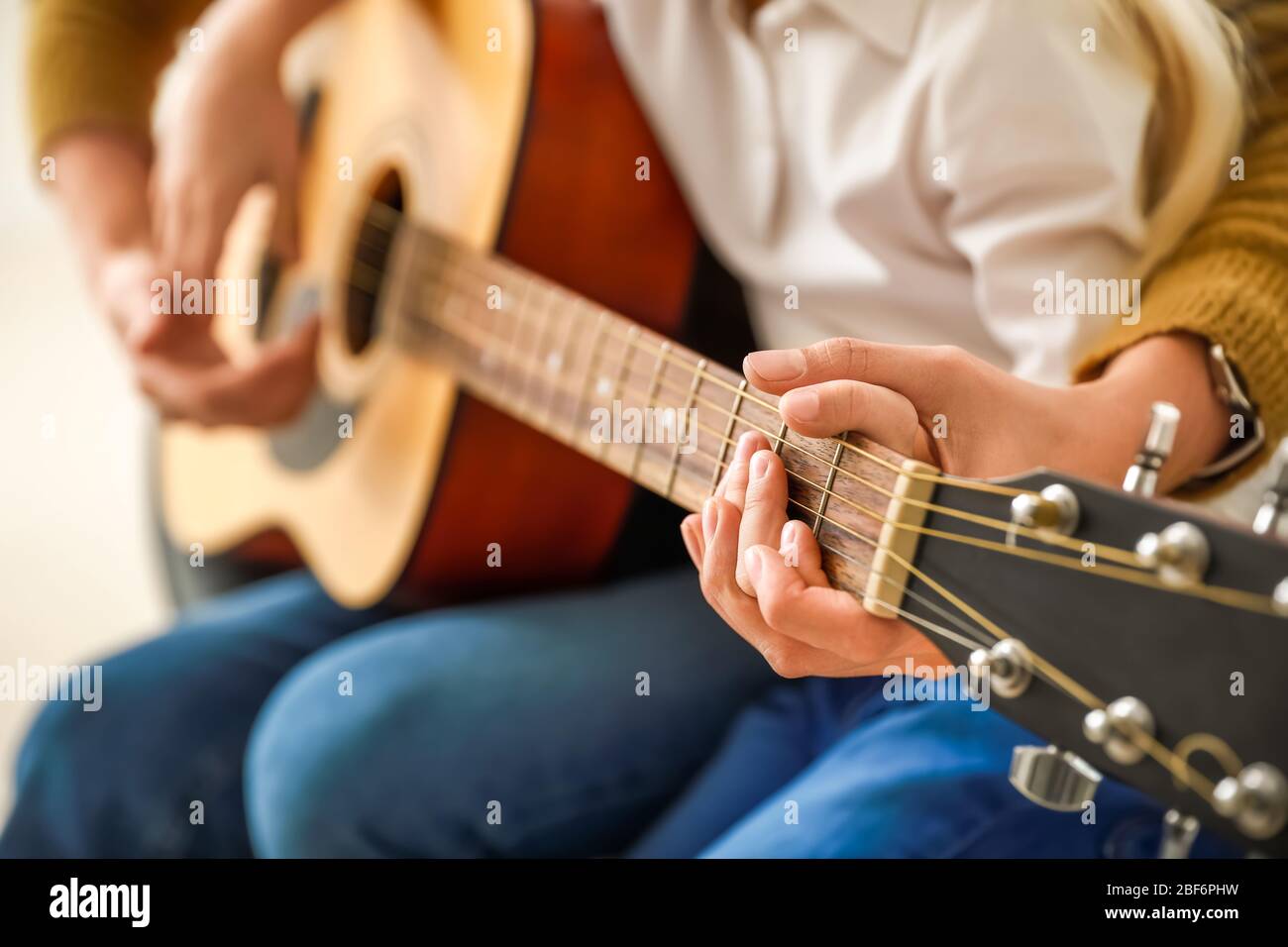 Private music teacher giving guitar lessons to little girl at home ...