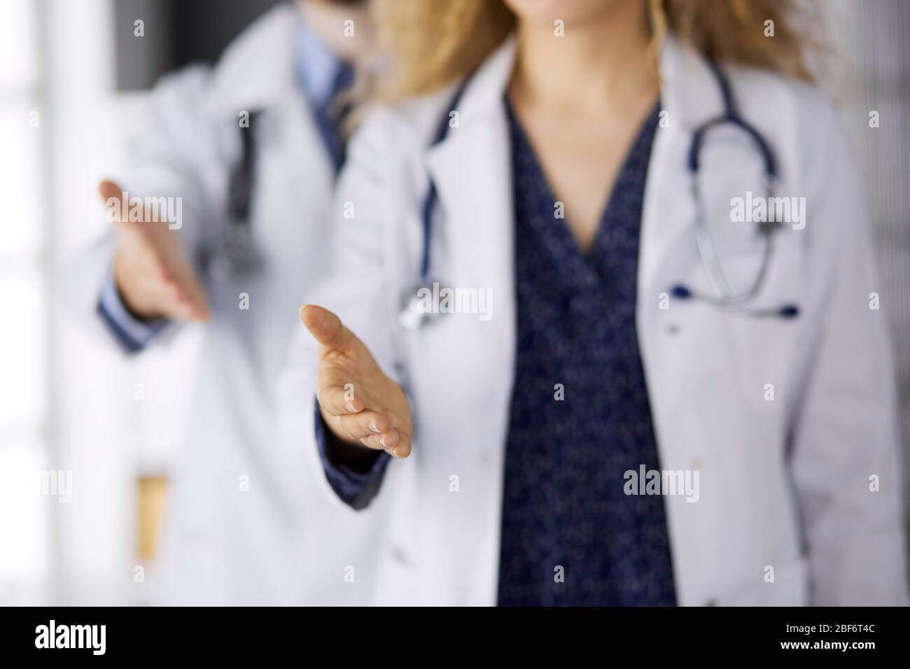 Two doctors standing and offering helping hand for shaking hand or ...