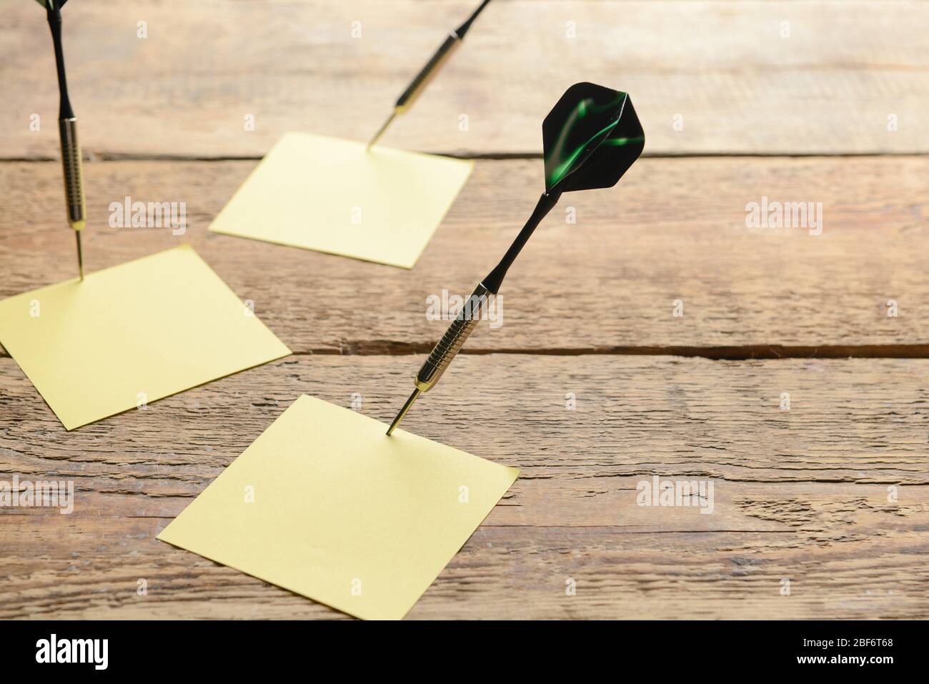 Darts with paper sheets on wooden background Stock Photo - Alamy