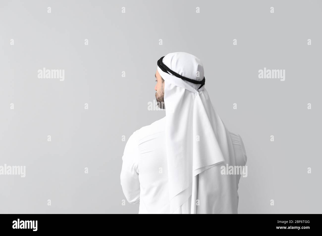 Handsome Arab man on grey background, back view Stock Photo - Alamy