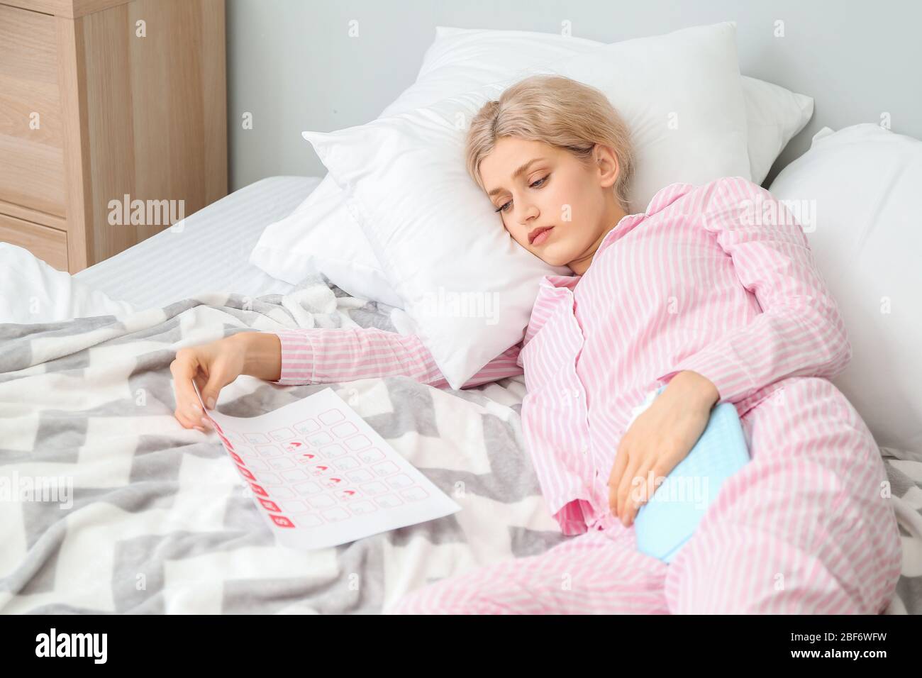 Young woman suffering from menstrual cramps in bedroom Stock Photo - Alamy