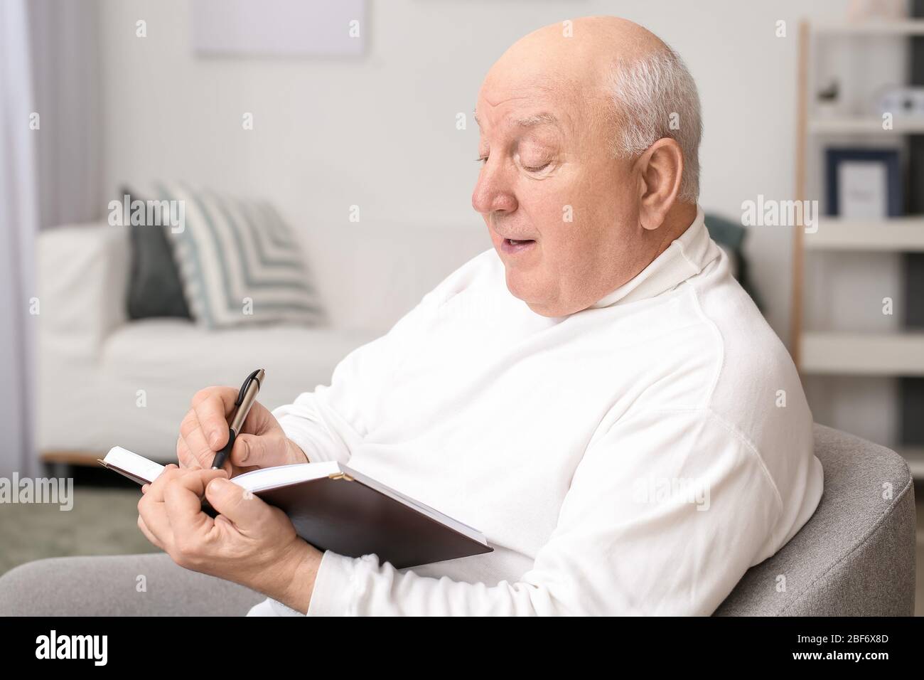 Portrait of elderly man writing in notebook at home Stock Photo - Alamy