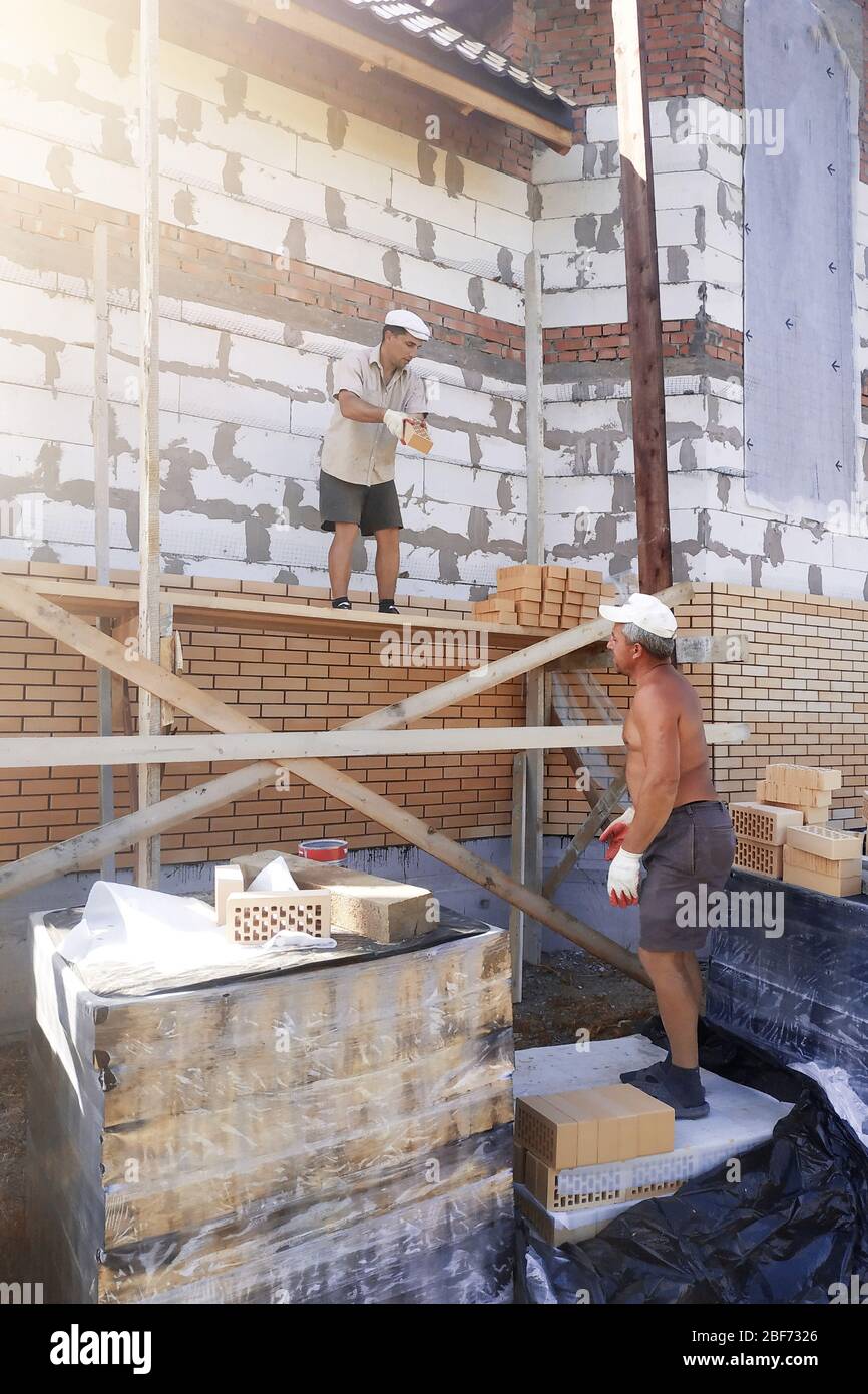 The master throws a brick at his worker for laying the wall. 2019 Stock ...