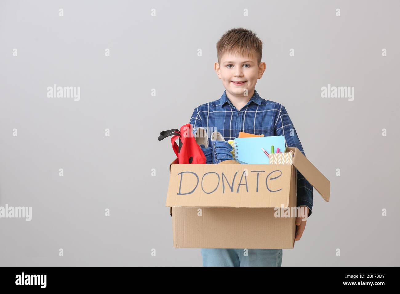 Little boy with donations on grey background Stock Photo - Alamy