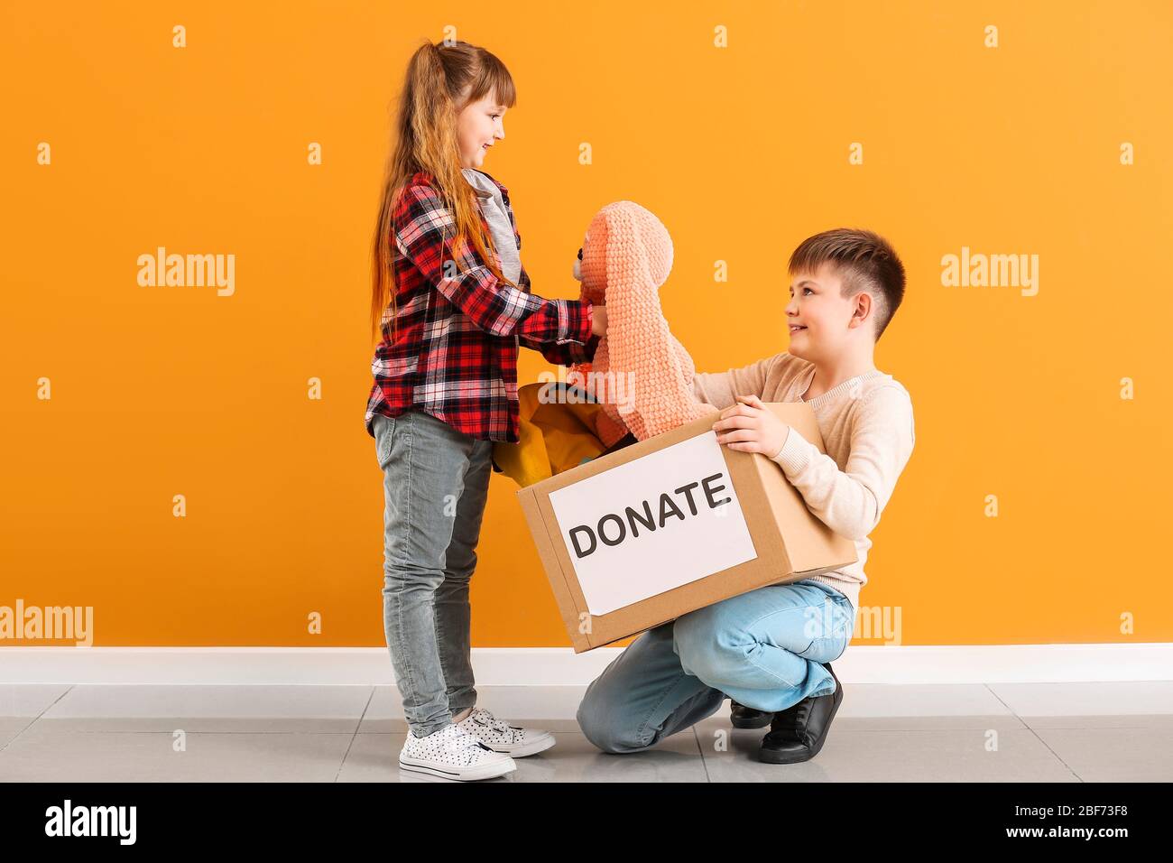 Little children with donations near color wall Stock Photo - Alamy