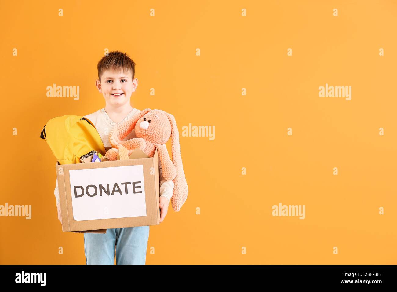 Little boy with donations on color background Stock Photo - Alamy