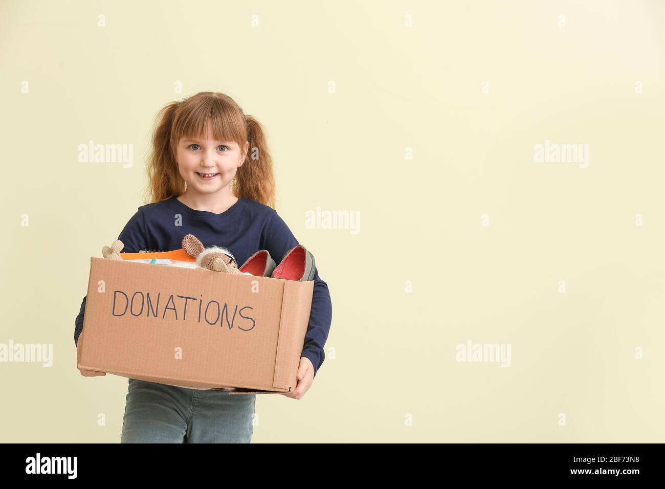 Little girl with donations on color background Stock Photo - Alamy
