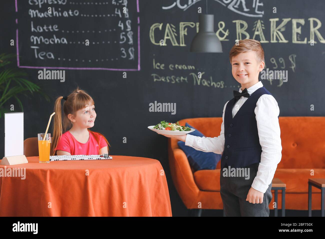 Cute little waiter serving client in restaurant Stock Photo - Alamy