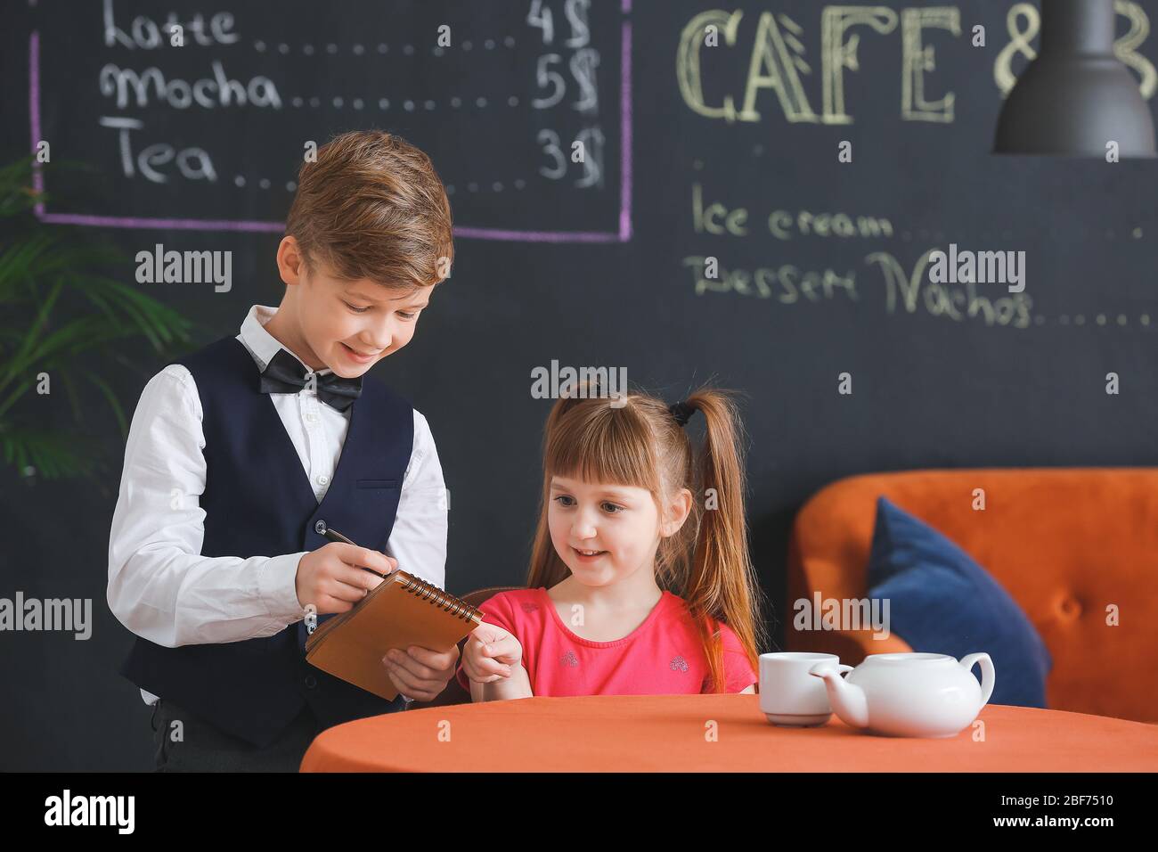 Cute little waiter serving client in restaurant Stock Photo - Alamy