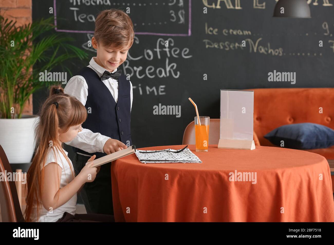 Cute little waiter serving client in restaurant Stock Photo - Alamy