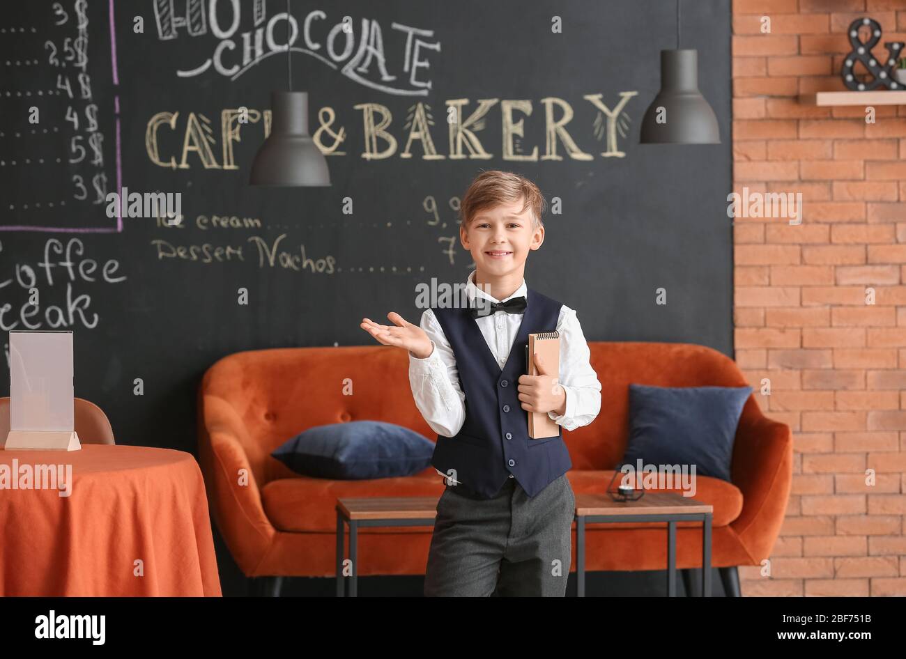 Cute little waiter in restaurant Stock Photo - Alamy