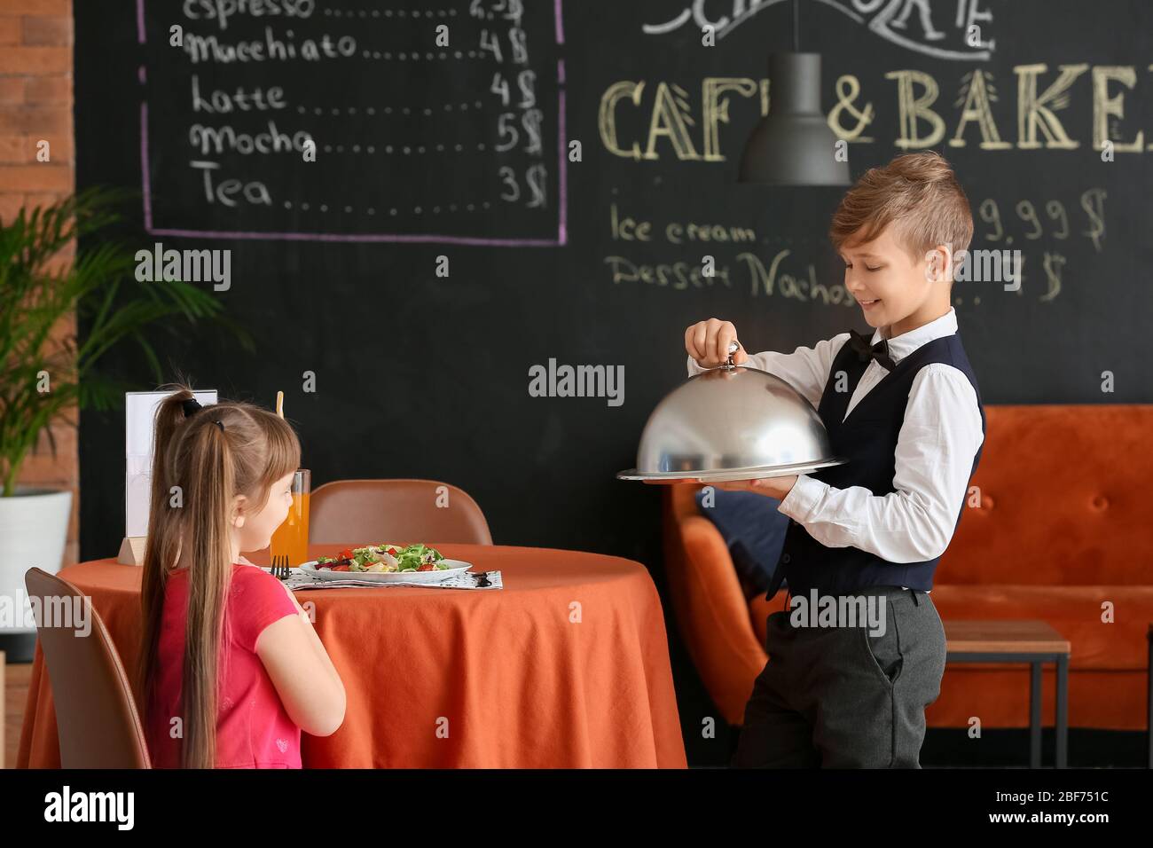 Cute little waiter serving client in restaurant Stock Photo - Alamy