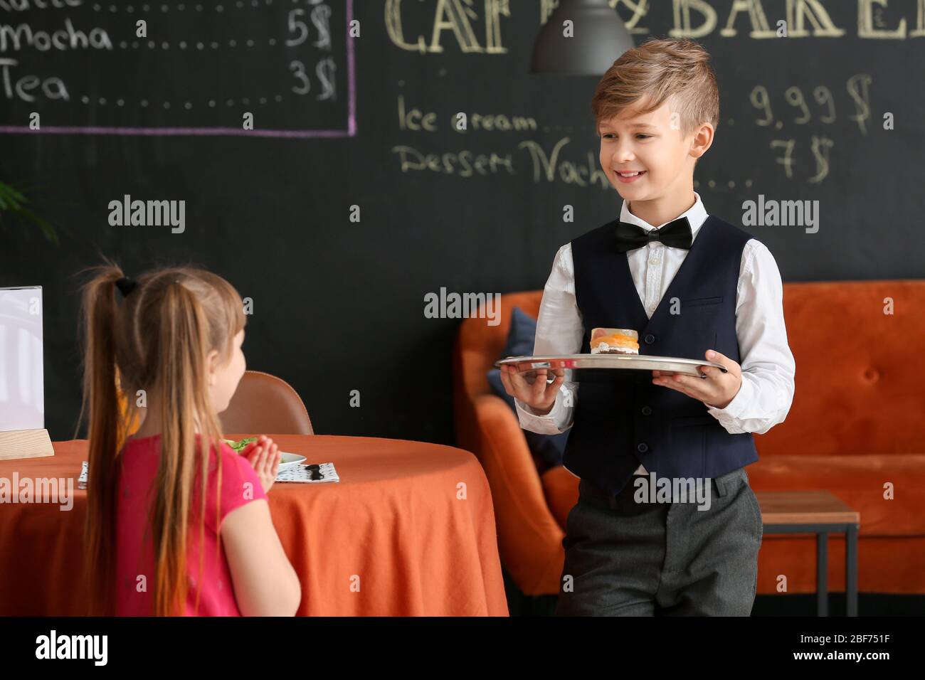 Cute little waiter serving client in restaurant Stock Photo - Alamy