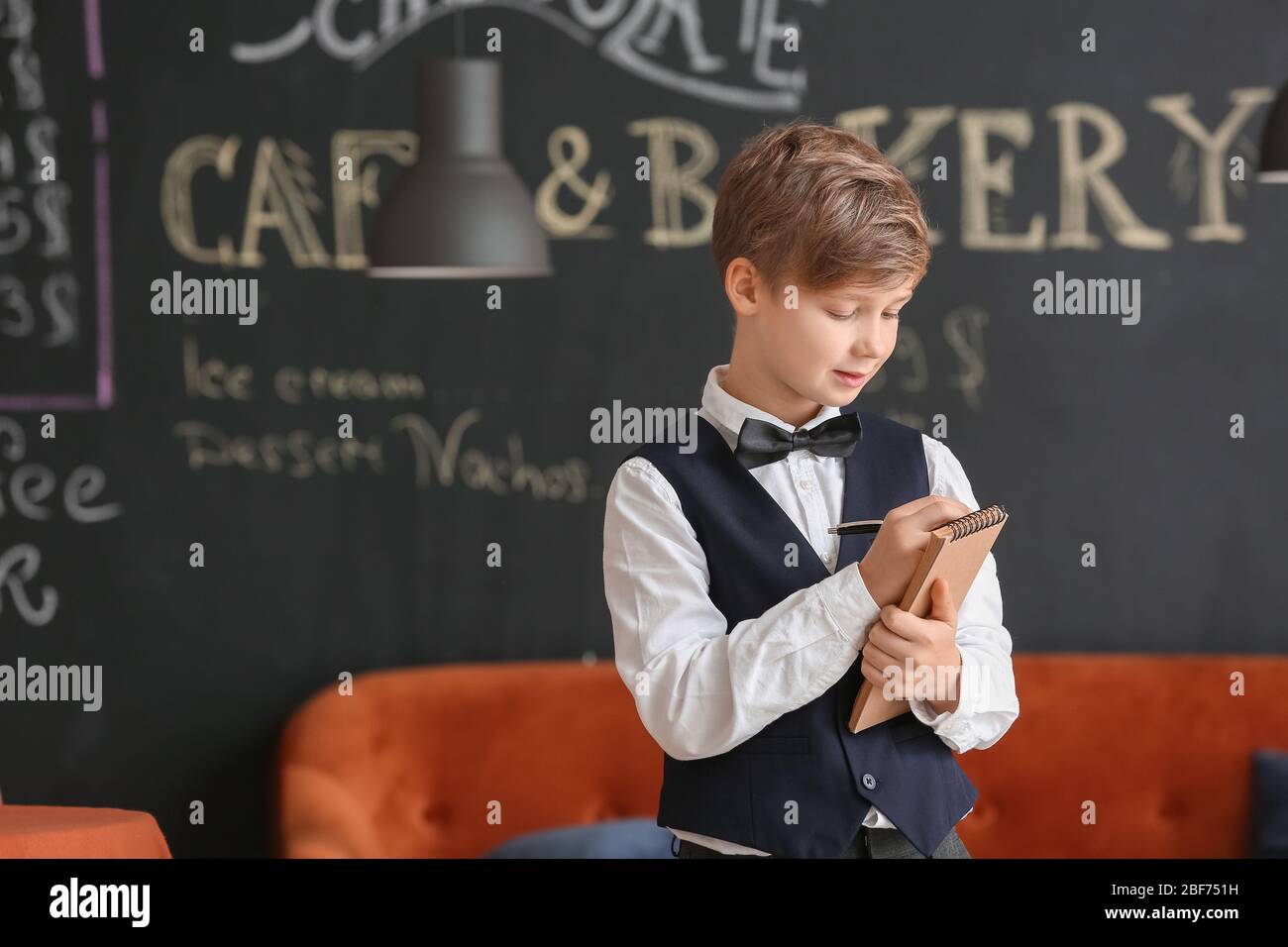 Cute little waiter in restaurant Stock Photo - Alamy