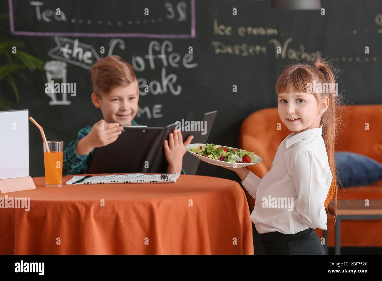 Cute little waiter serving client in restaurant Stock Photo - Alamy