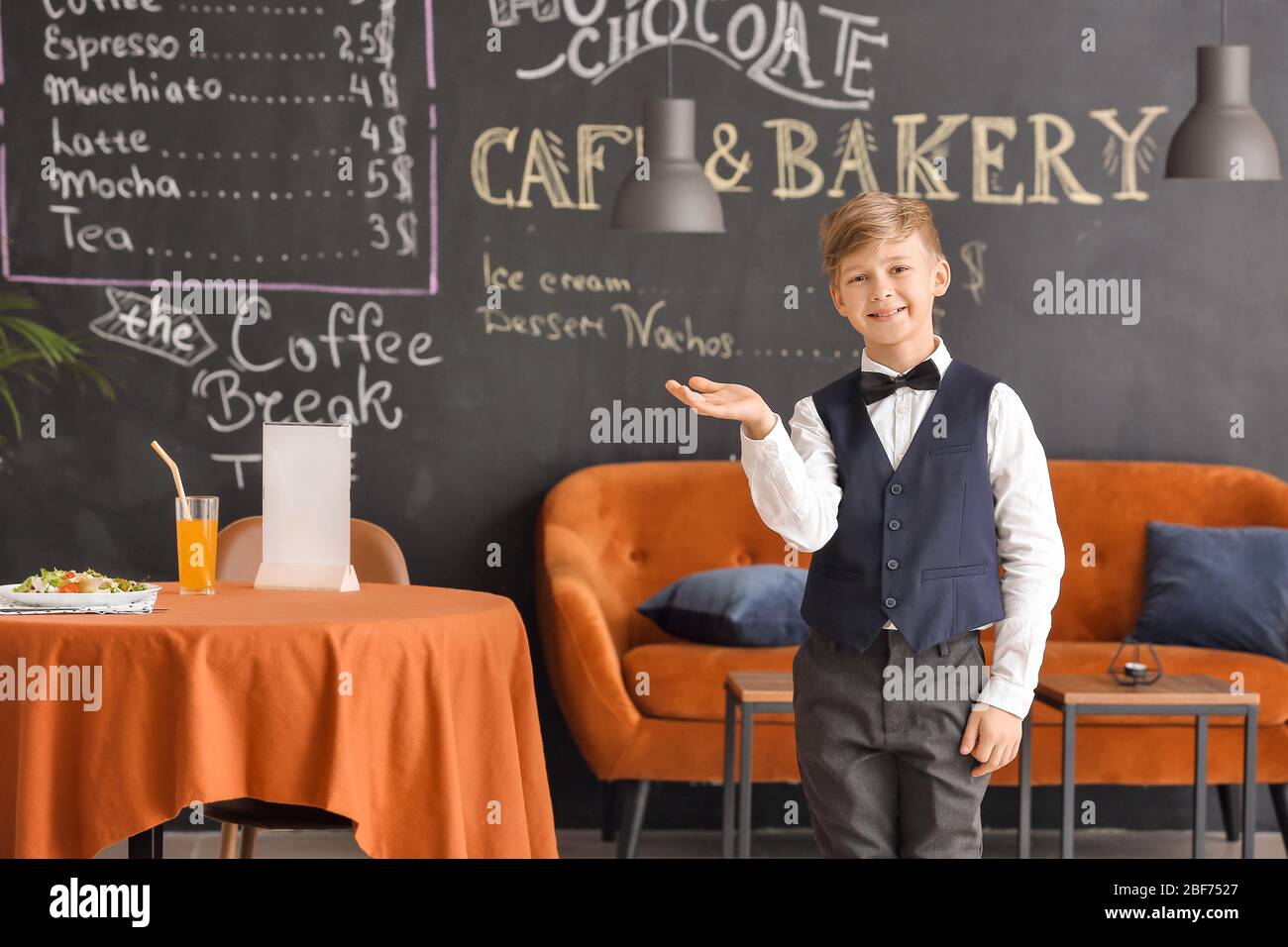 Cute little waiter in restaurant Stock Photo - Alamy