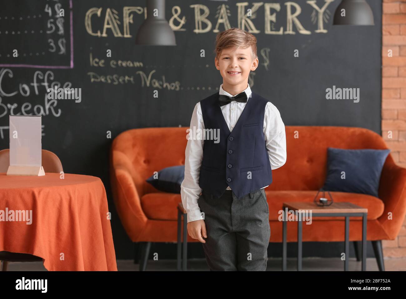 Cute little waiter in restaurant Stock Photo - Alamy