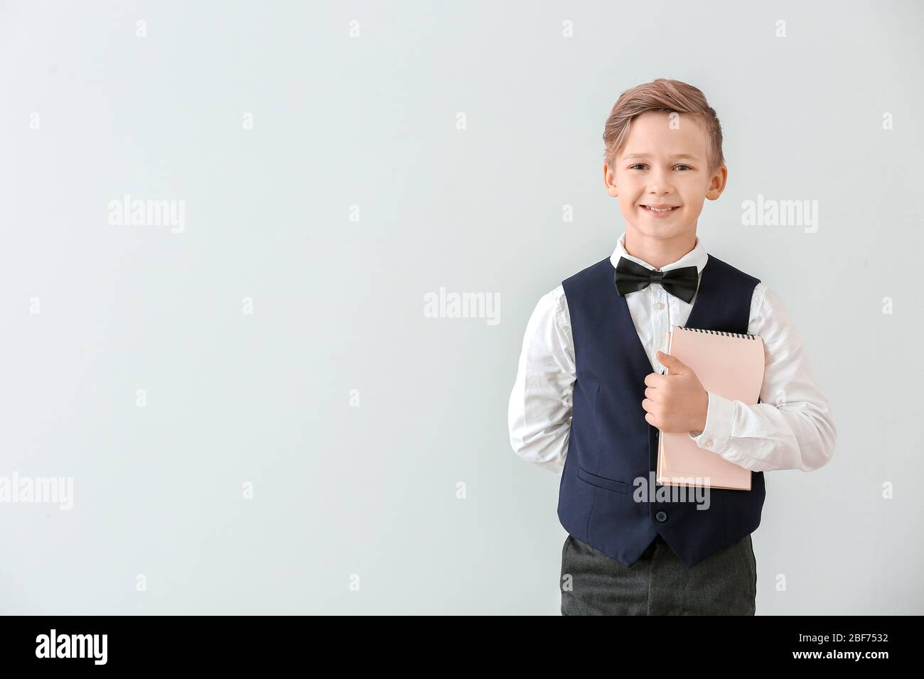 Cute little waiter on light background Stock Photo - Alamy