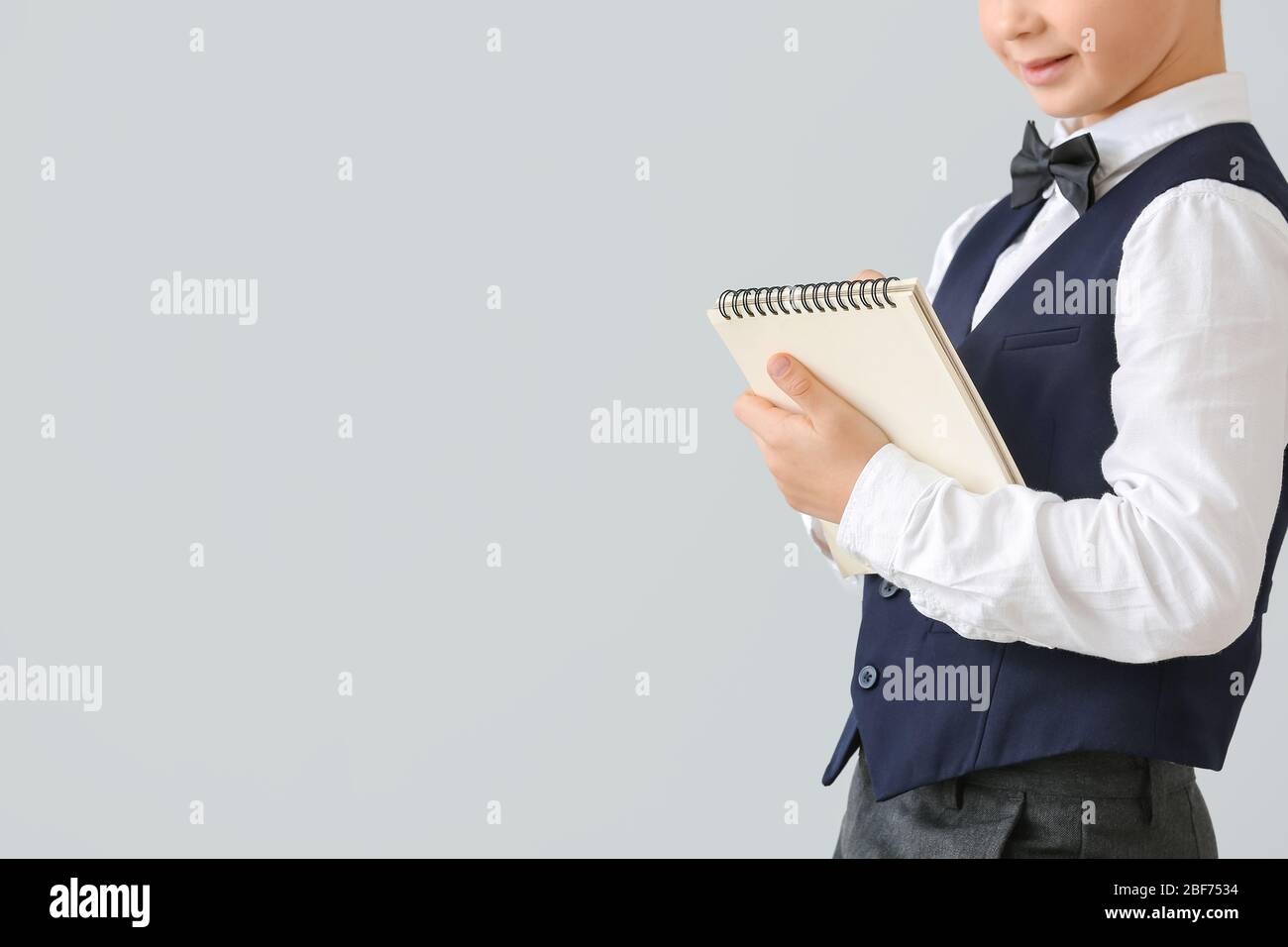Cute little waiter with notebook on light background Stock Photo - Alamy