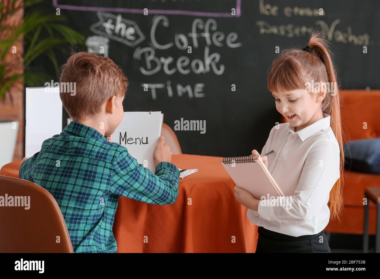 Cute little waiter serving client in restaurant Stock Photo - Alamy