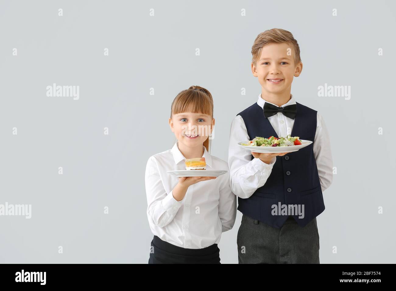 Cute little waiters on light background Stock Photo - Alamy