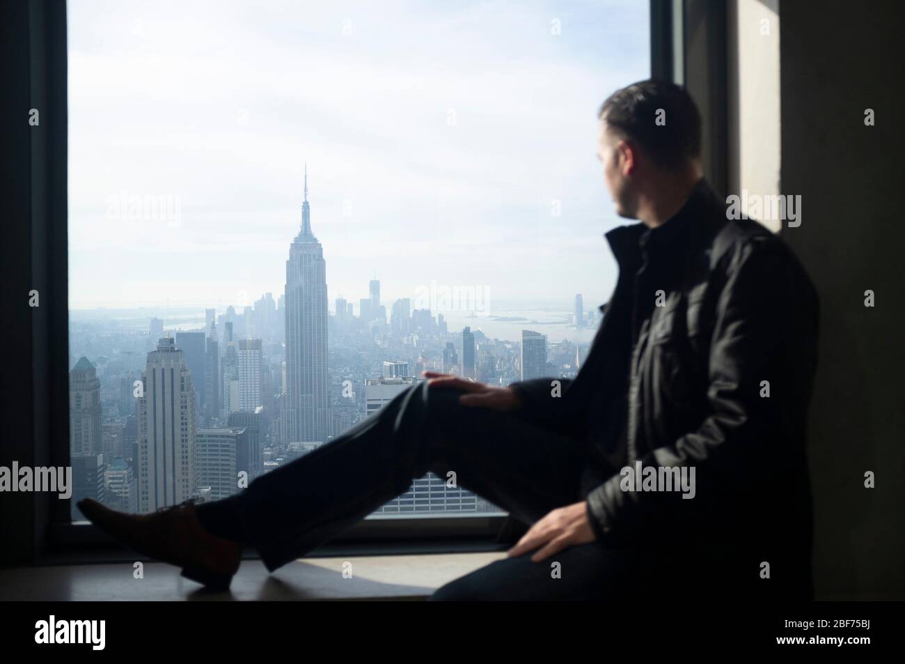 Man looking out the window. The Empire State Building and Manhattan ...