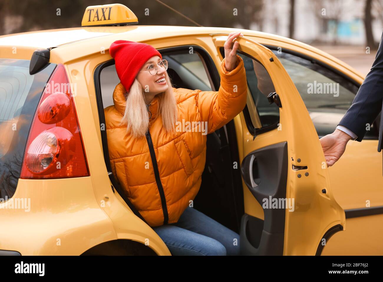 Driver helping young woman to get out of taxi Stock Photo - Alamy