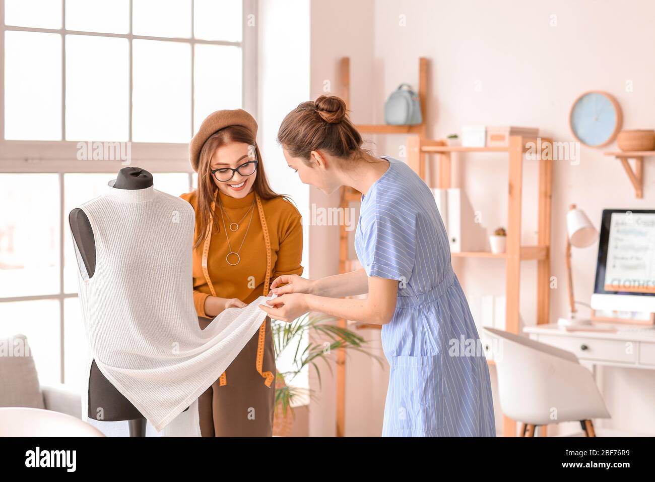 Young female tailor with ordering customer in atelier Stock Photo - Alamy