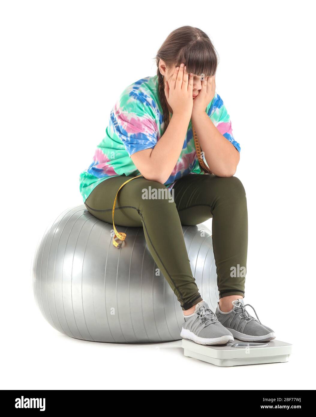 Sad overweight girl with measuring scales and fitness ball on white ...