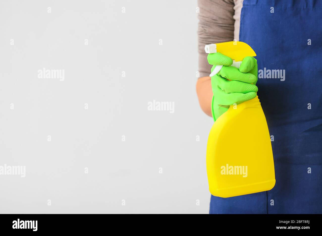 Janitor with detergent on light background Stock Photo - Alamy