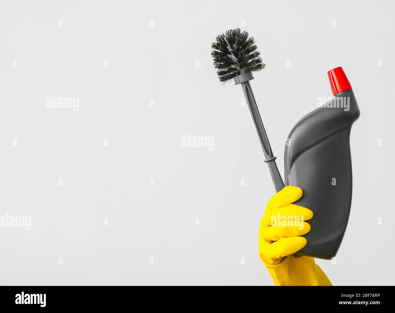 Hand of janitor with detergent and toilet brush on light background ...