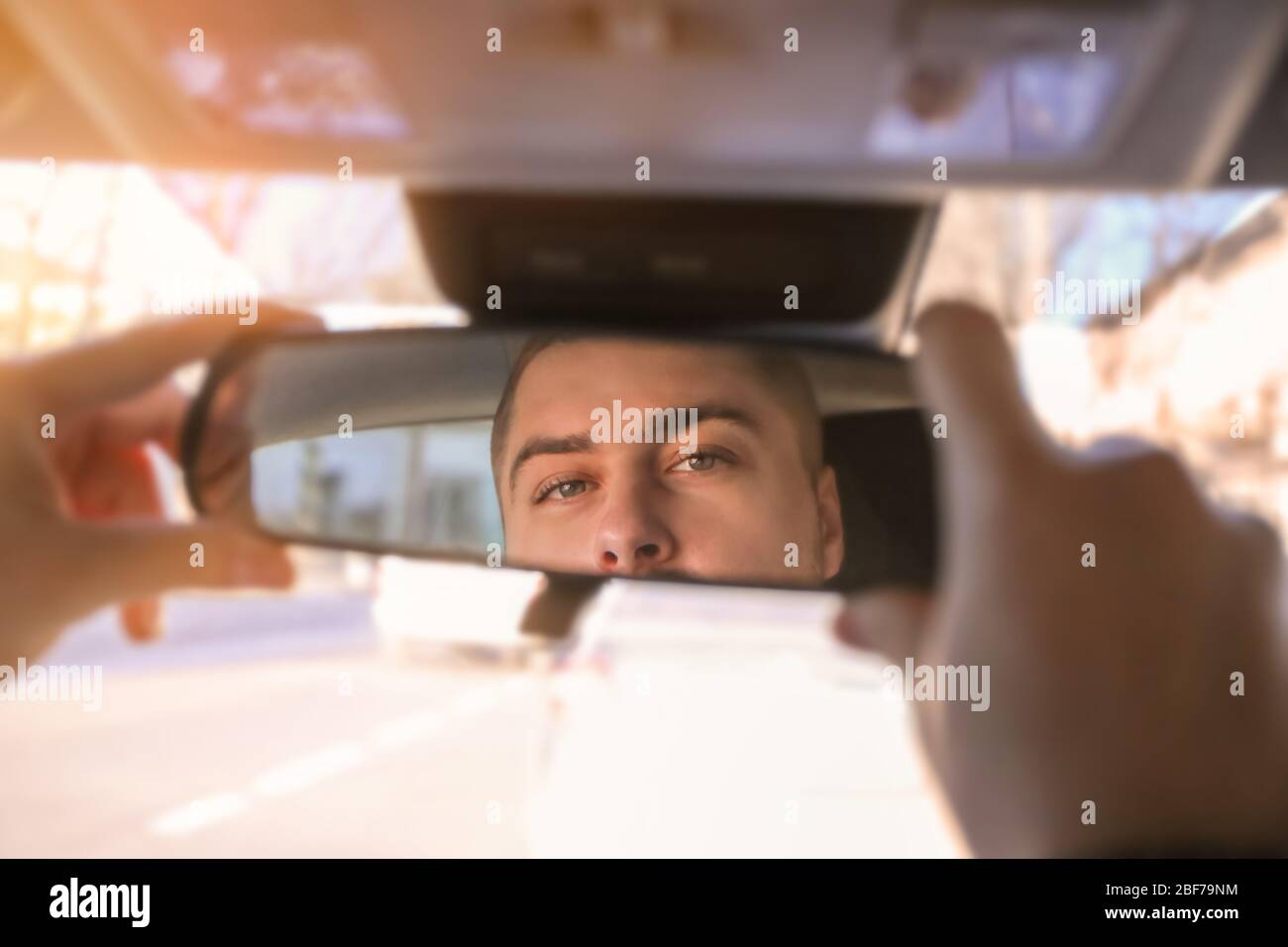 Driver adjusting rear view mirror in car Stock Photo - Alamy