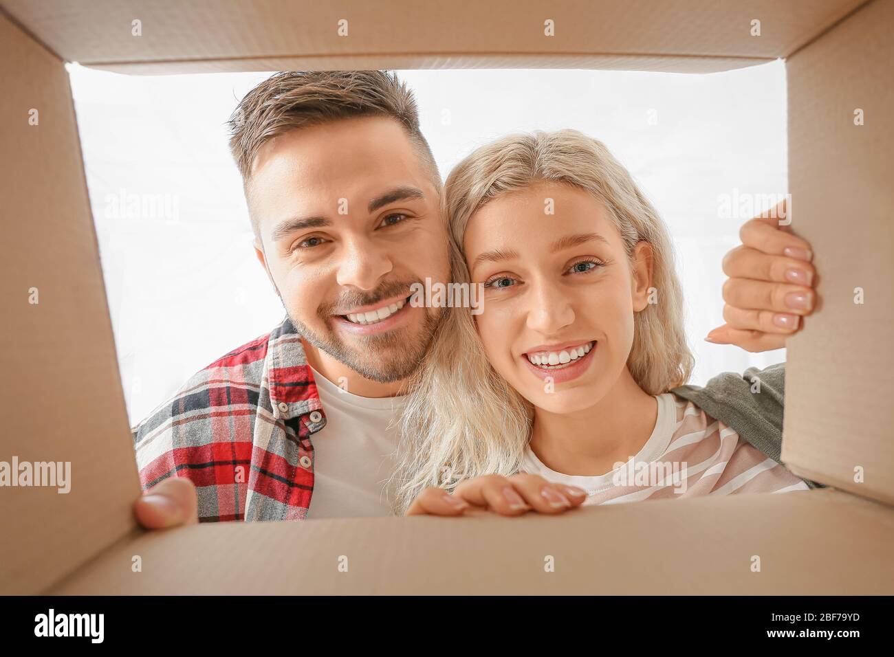 Happy young couple with open moving box, view from inside Stock Photo ...