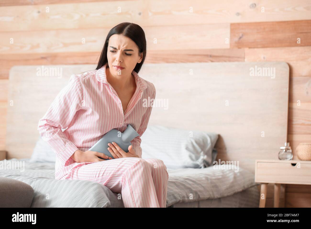 Young woman suffering from menstrual cramps in bedroom Stock Photo - Alamy