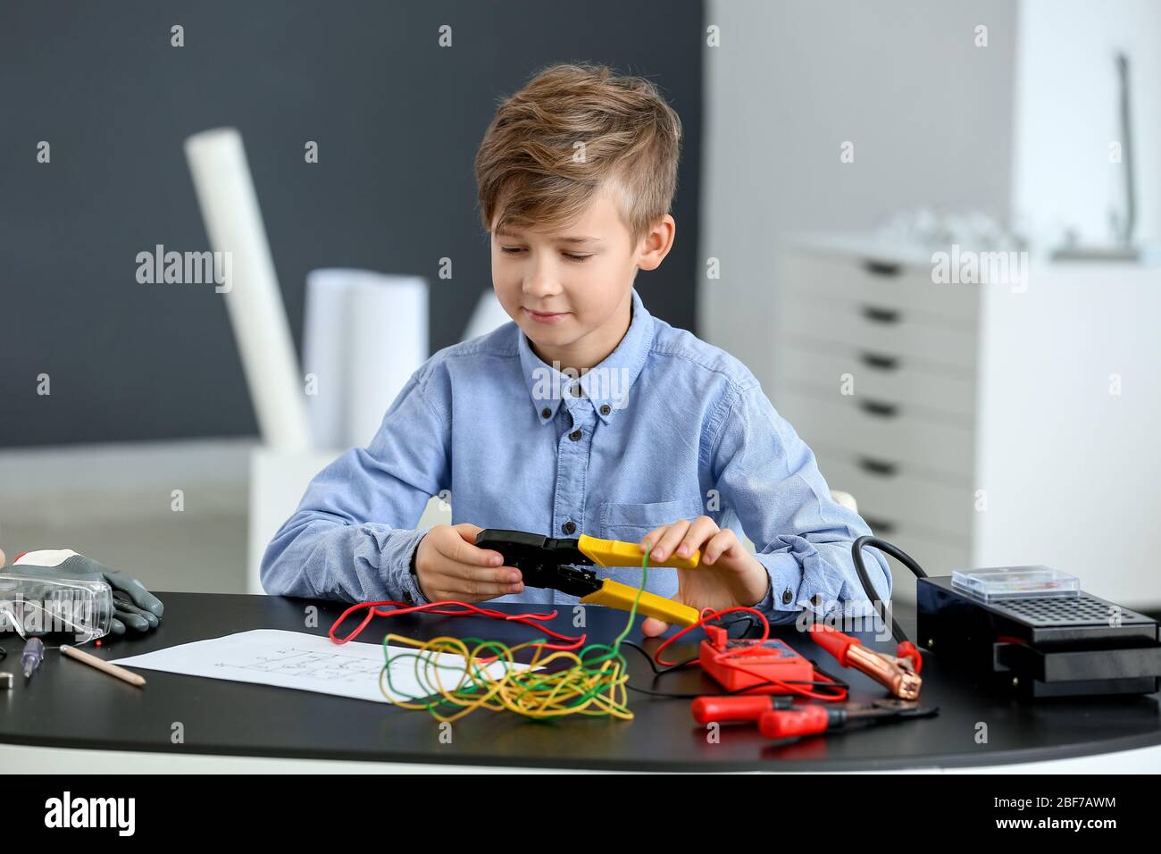 Cute little electrician performing wiring at table Stock Photo - Alamy