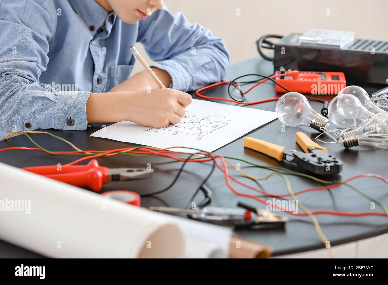 Cute little electrician drawing circuit diagram at table Stock Photo ...