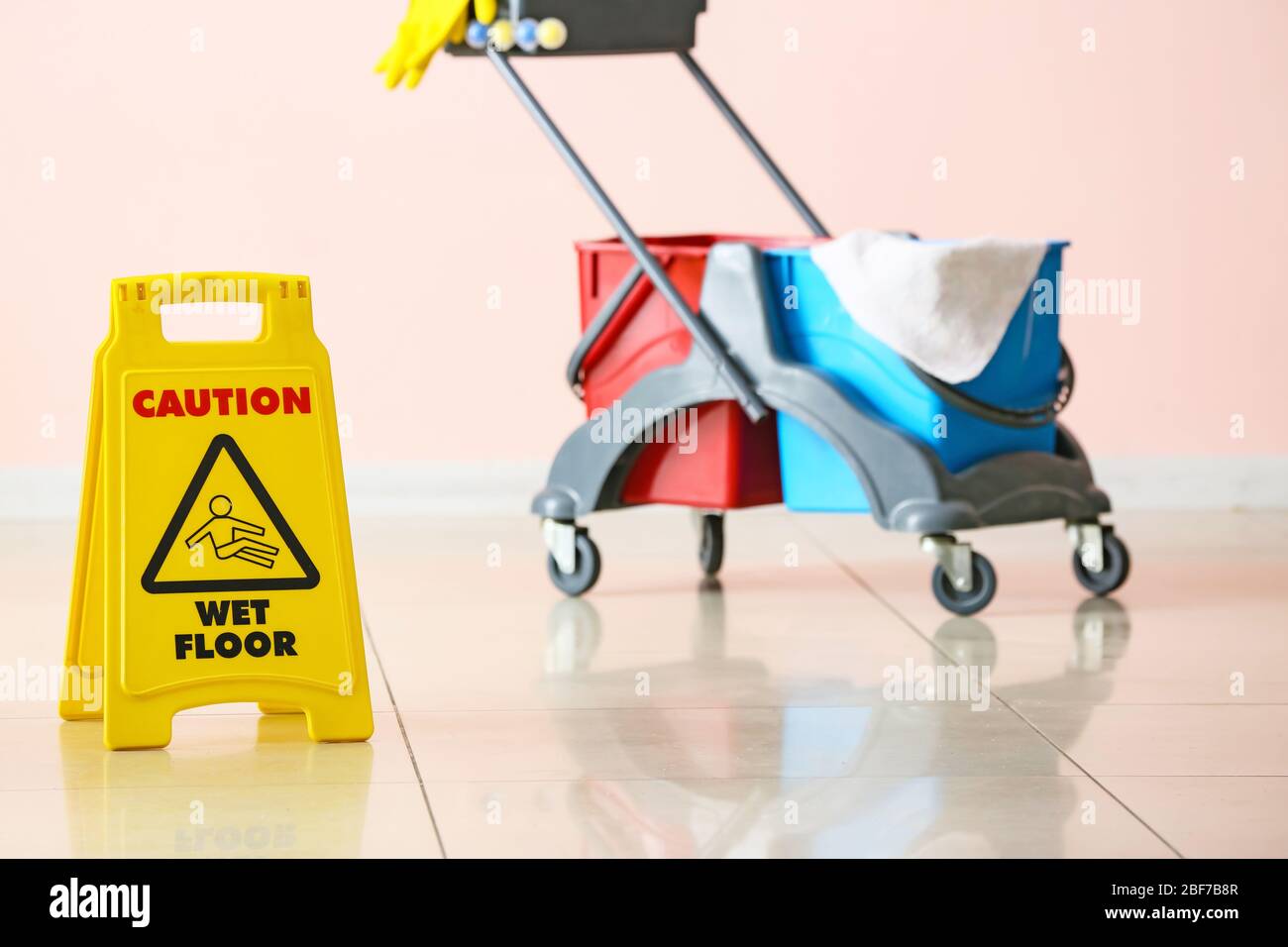 Caution sign with janitor's trolley indoors Stock Photo - Alamy