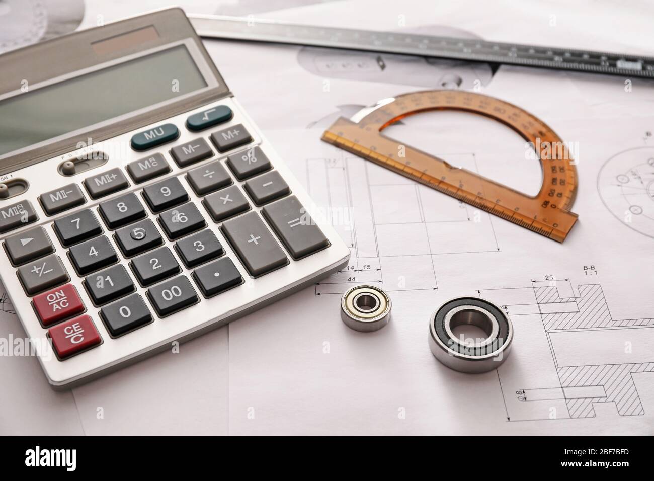 Bearings with calculator, protractor and drawings on table of engineer ...
