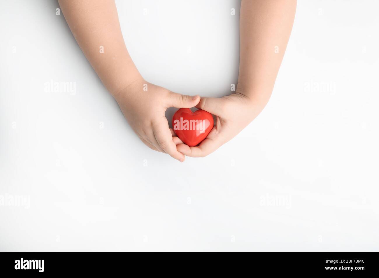 Child's hands with red heart on white background. Cardiology concept ...