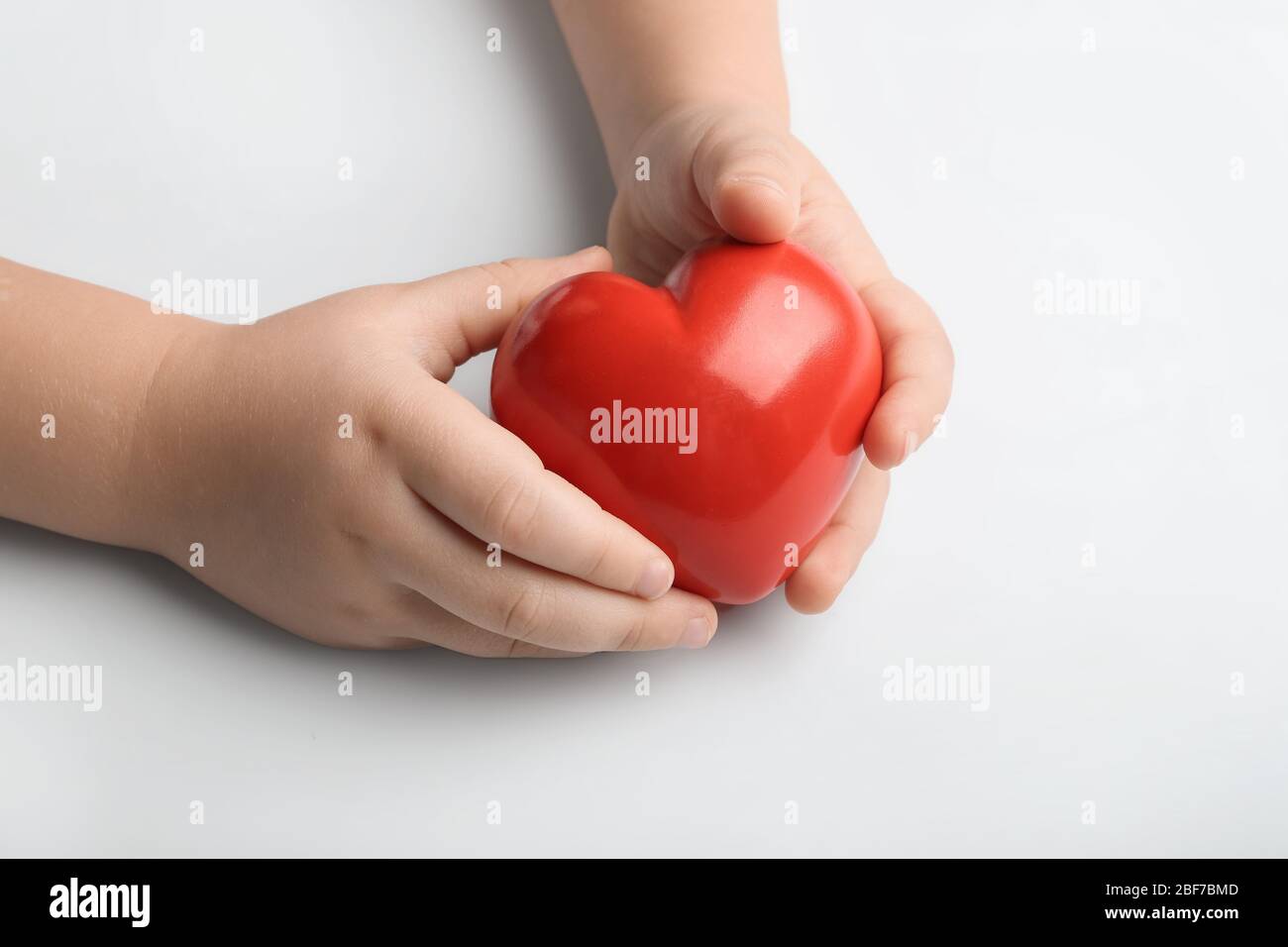 Child's hands with red heart on white background. Cardiology concept ...