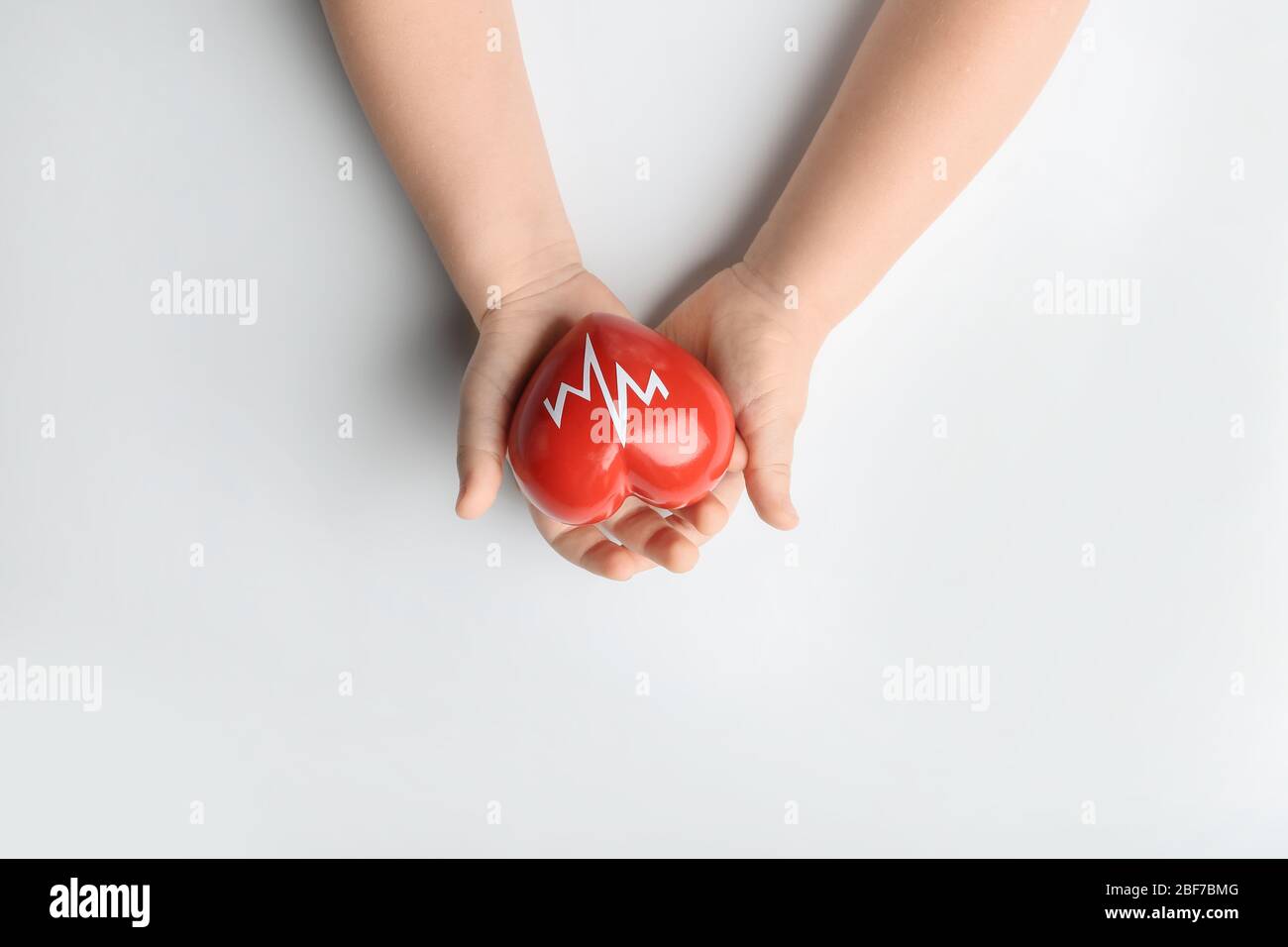 Child's hands with red heart on white background. Cardiology concept ...