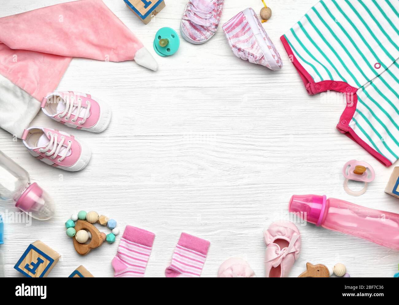 Frame made of baby clothes and accessories on white wooden background ...
