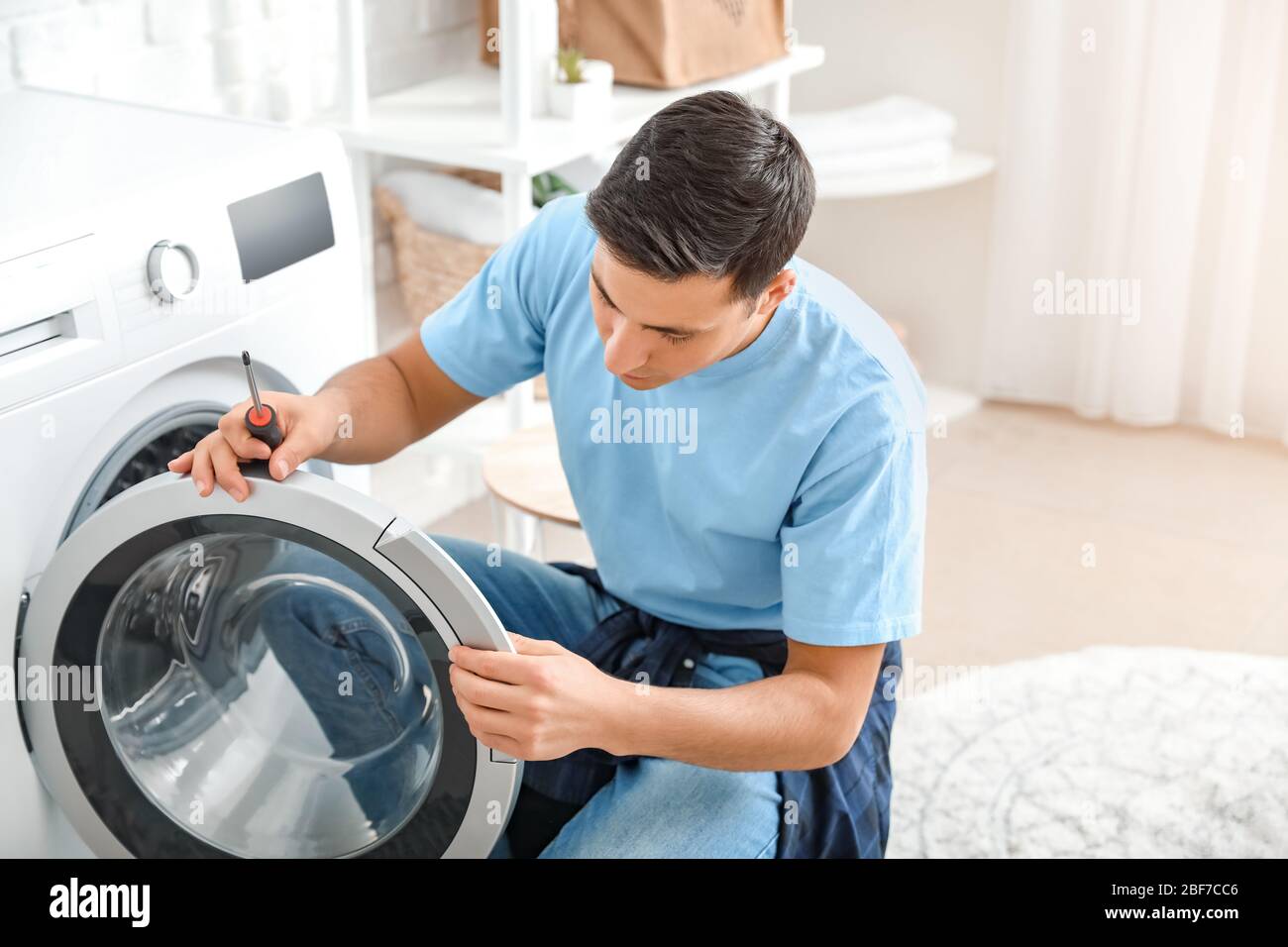 Worker repairing washing machine in laundry room Stock Photo - Alamy